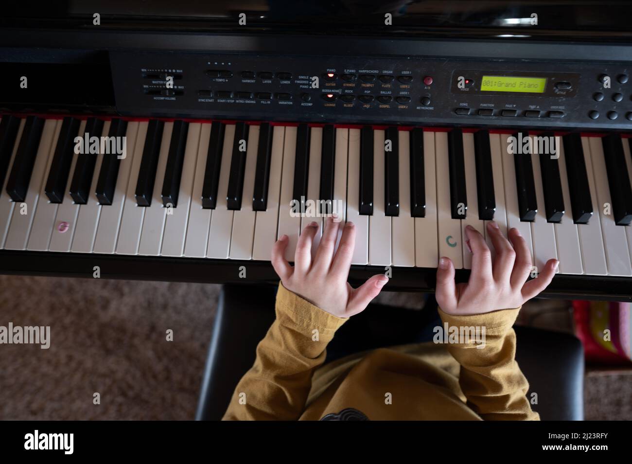 Young child practicing playing a piano with hands resting on keys Stock ...