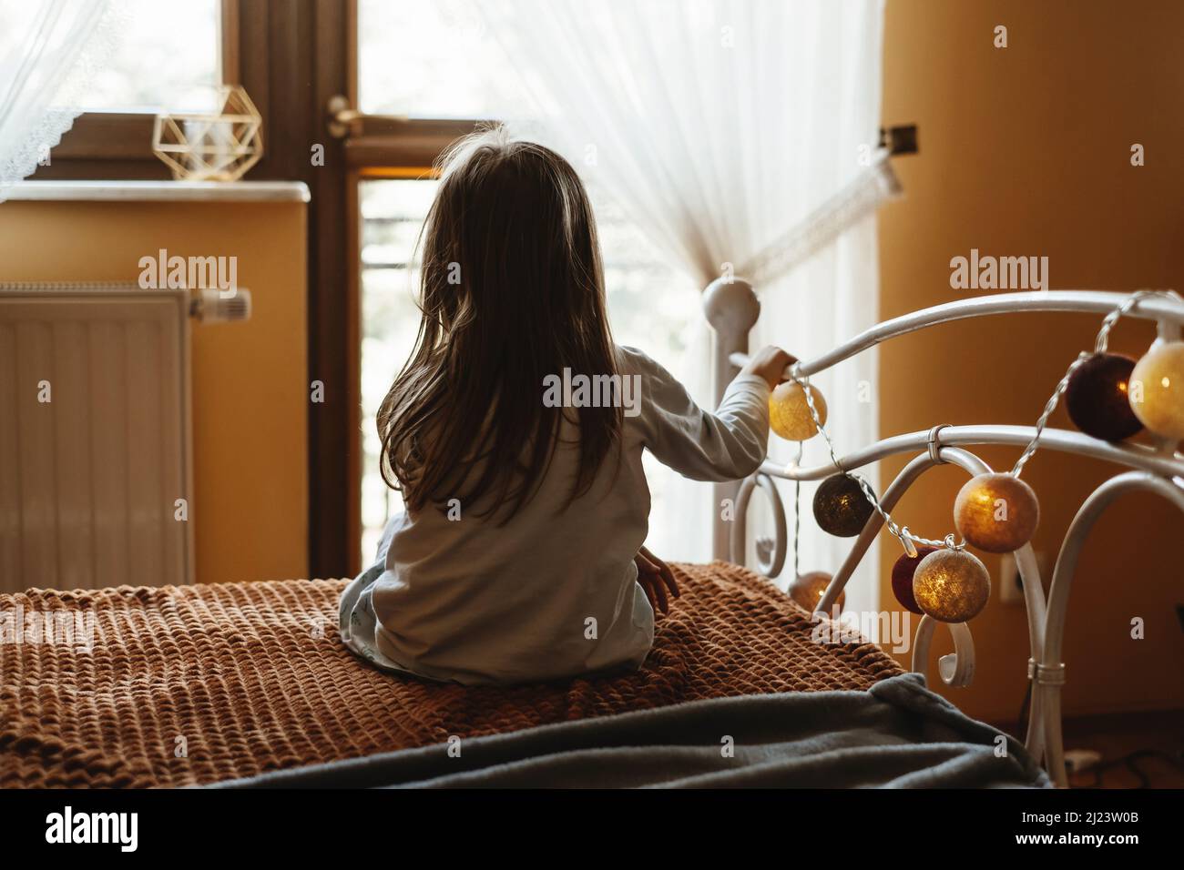 Child sitting on the bed at home. Dreamy sunny mood. Girl looking ...