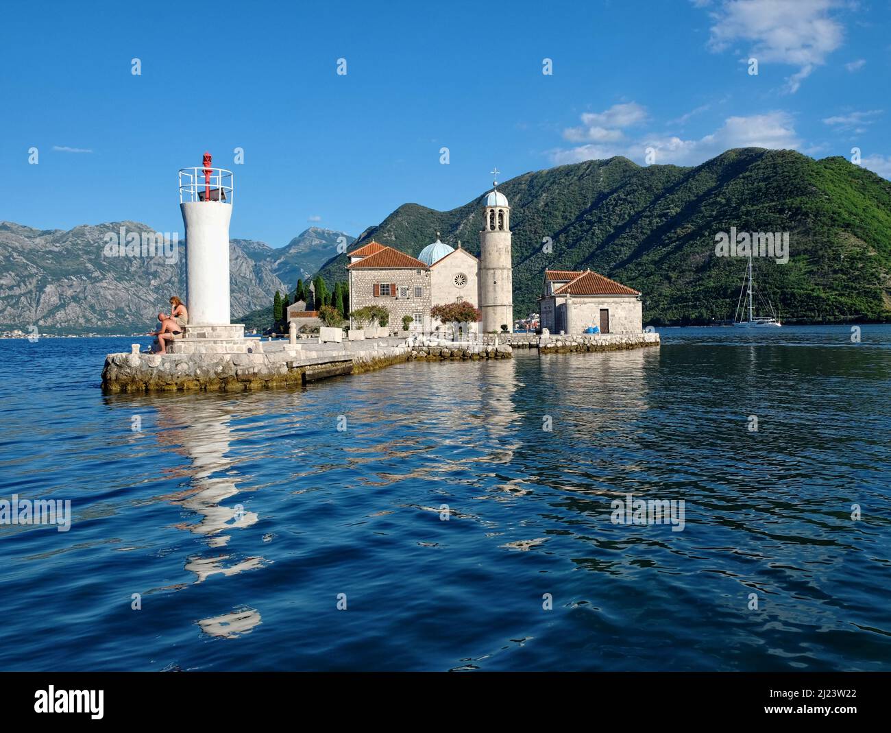 islet of the church Our Lady of the Rocks and white lighthouse ...