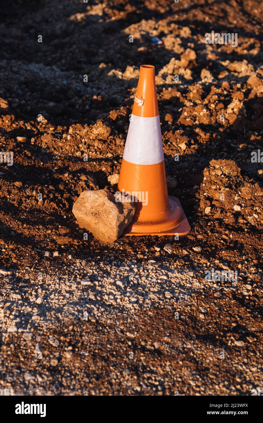 detail of an orange construction site cone with a stone to indicate a ...