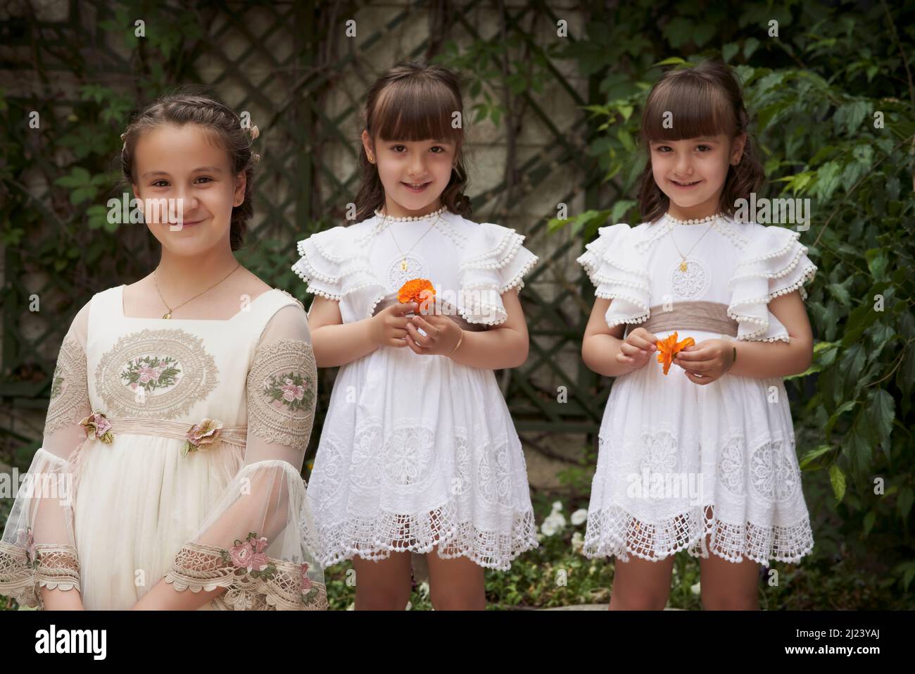 Communion girl posing with her twin little sisters in a park Stock ...