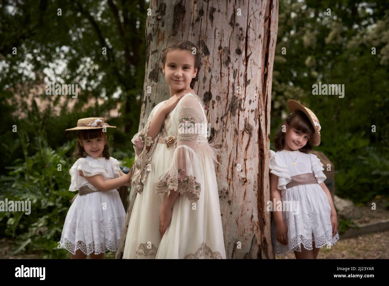 Communion girl posing with her twin little sisters in a park Stock ...