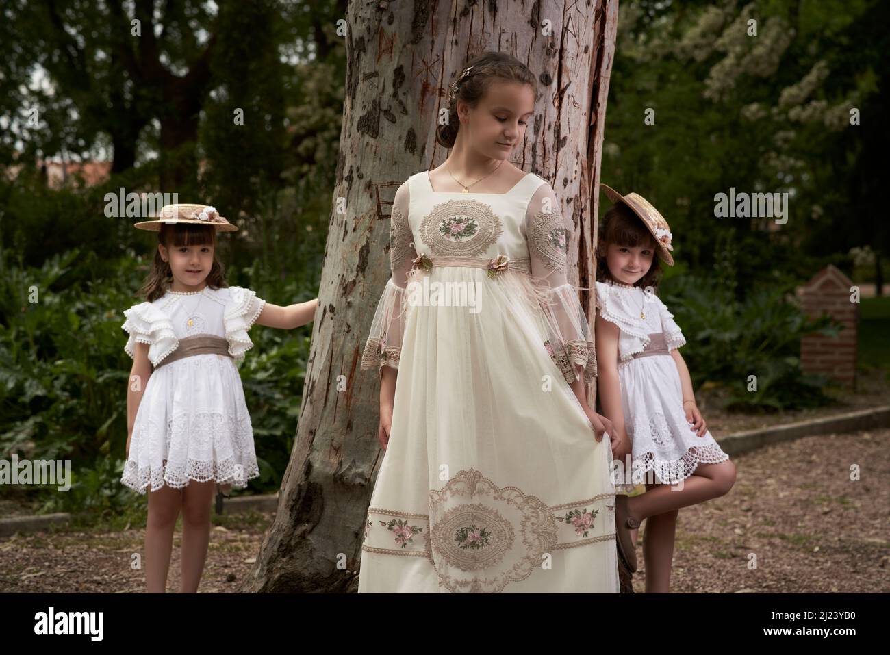 Communion girl posing with her twin little sisters in a park Stock ...