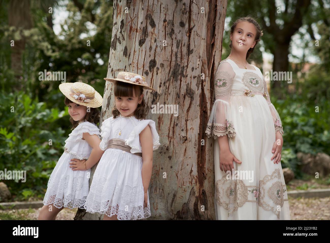 Communion girl posing with her twin little sisters in a park Stock ...