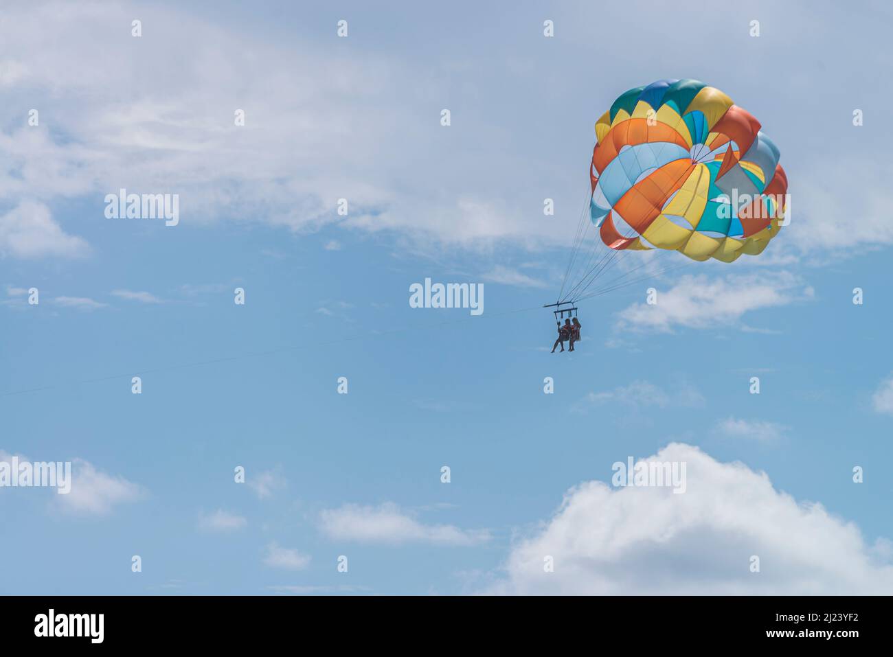 Couple of adults parasailing with a big colorful parachute Stock Photo ...