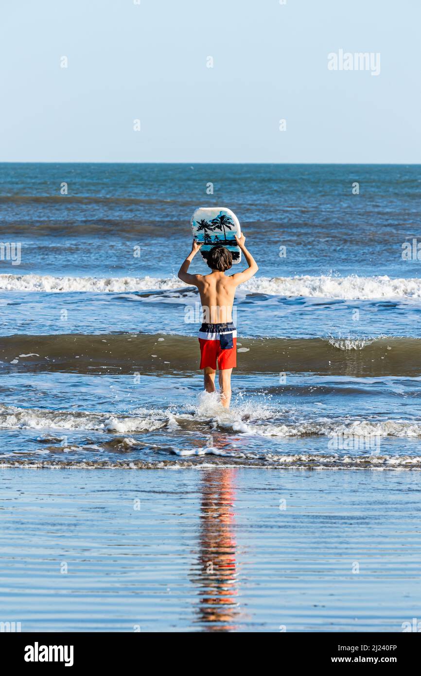 Teenage Boy Standing in the Ocean Holding a Bodyboard on his Head Stock ...