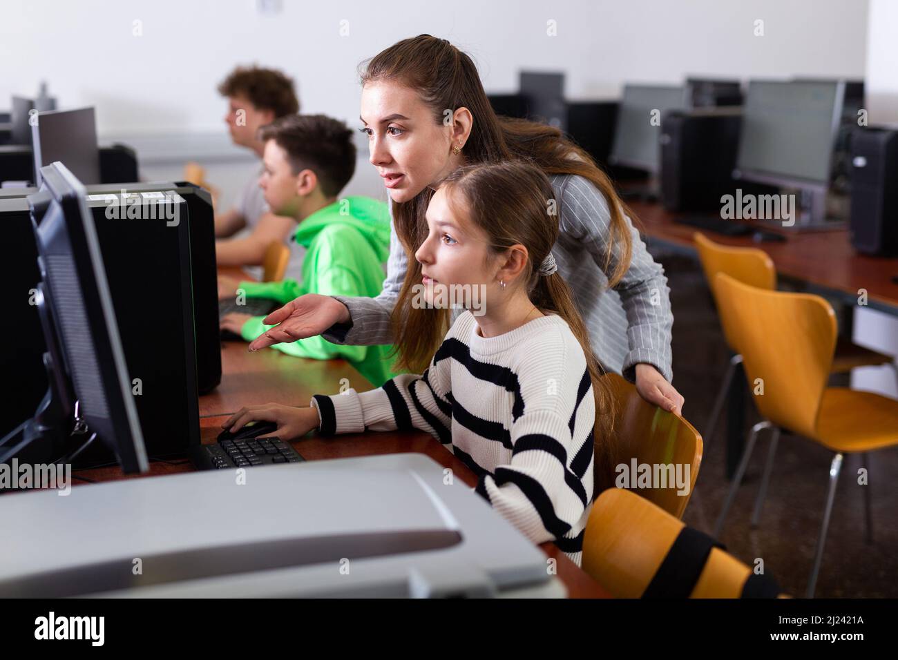 Teacher helping girl to solve computer problem Stock Photo - Alamy
