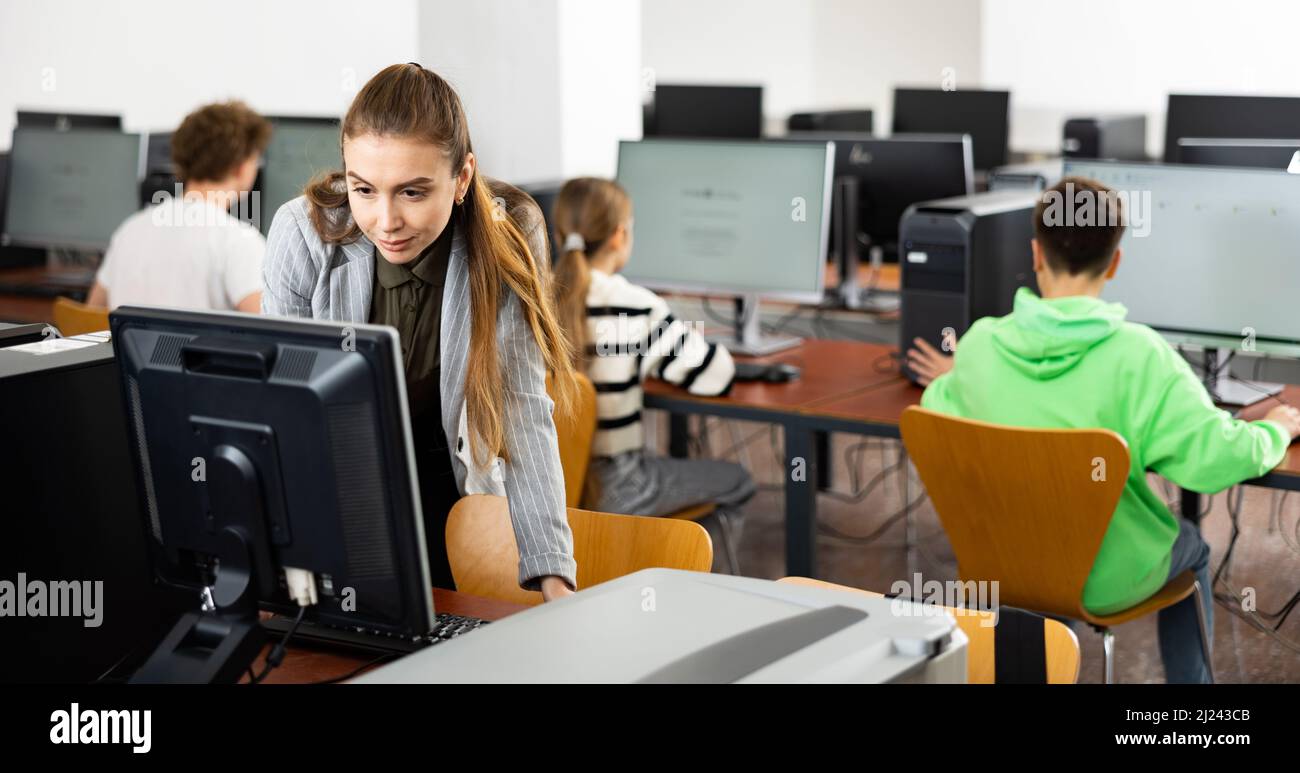 Young woman teacher using PC during lesson Stock Photo - Alamy
