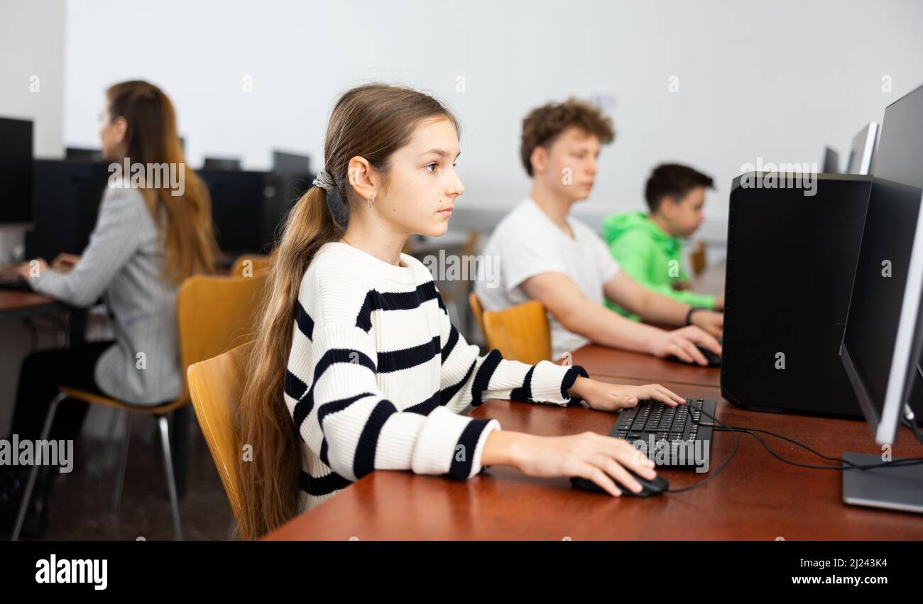 Teen schoolgirl learning basics of programming in computer college ...