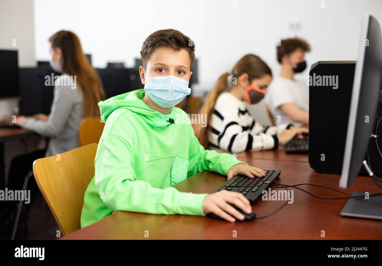Young boy in mask using computer during lesson Stock Photo - Alamy