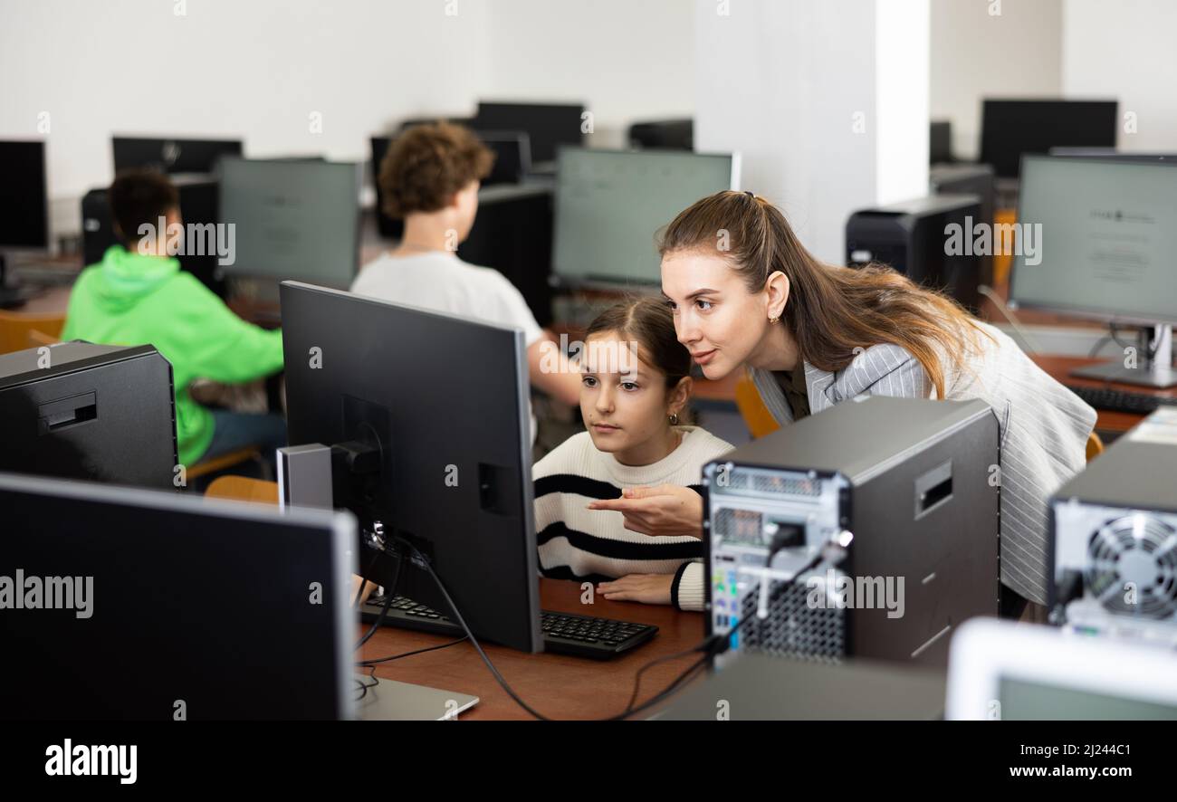 Positive woman teacher together with the girl teaches how to work on ...