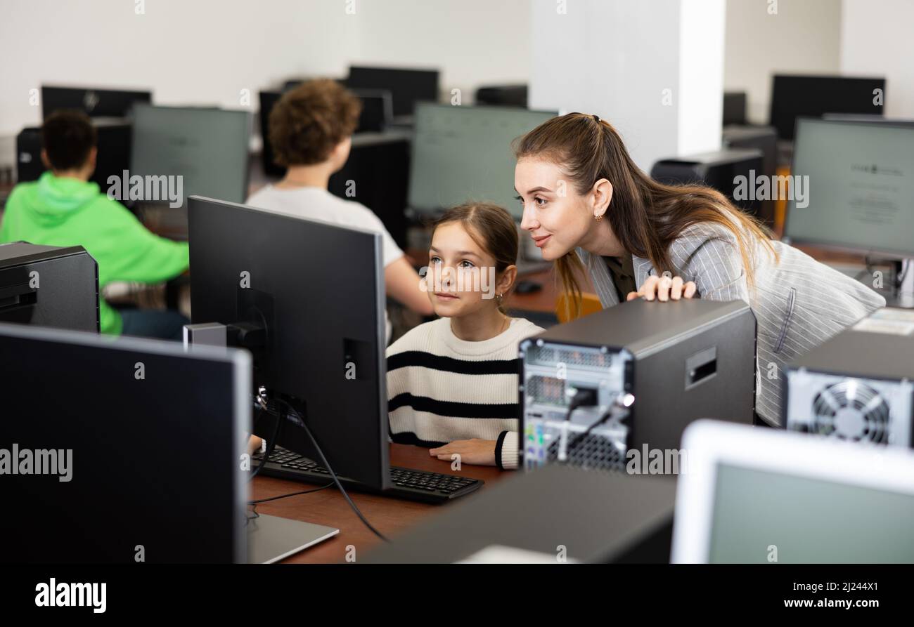Teacher explaining task solution to pupil during computer science ...