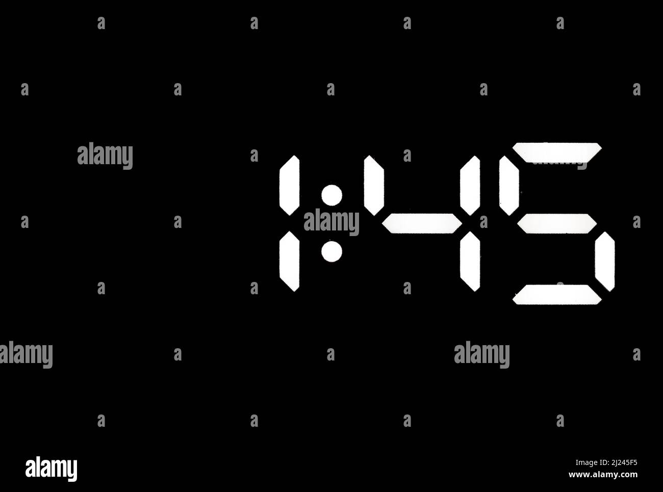 Real white led digital clock on a black background showing time 1:45 ...