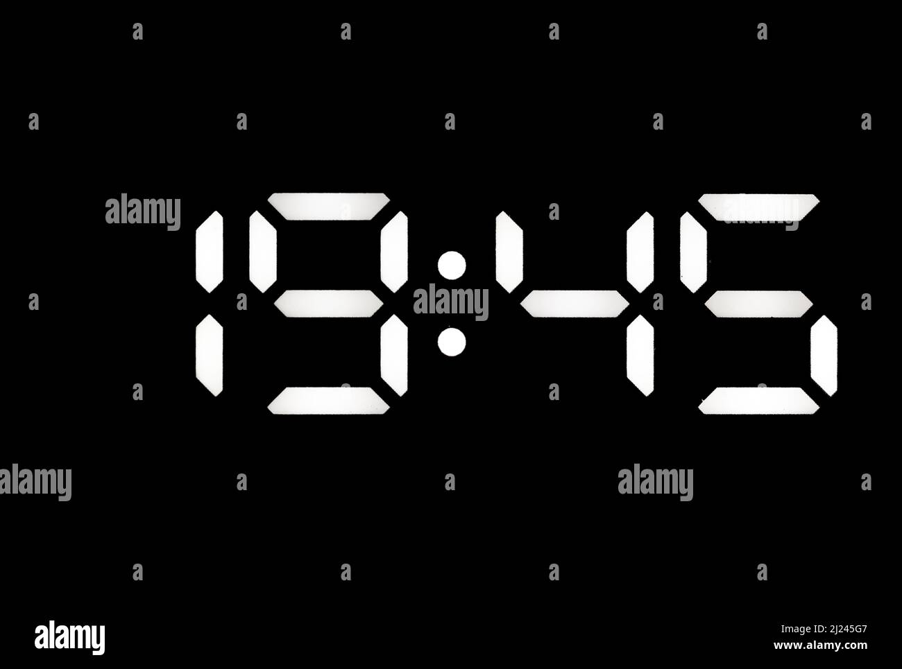 Real white led digital clock on a black background showing time 19:45 ...