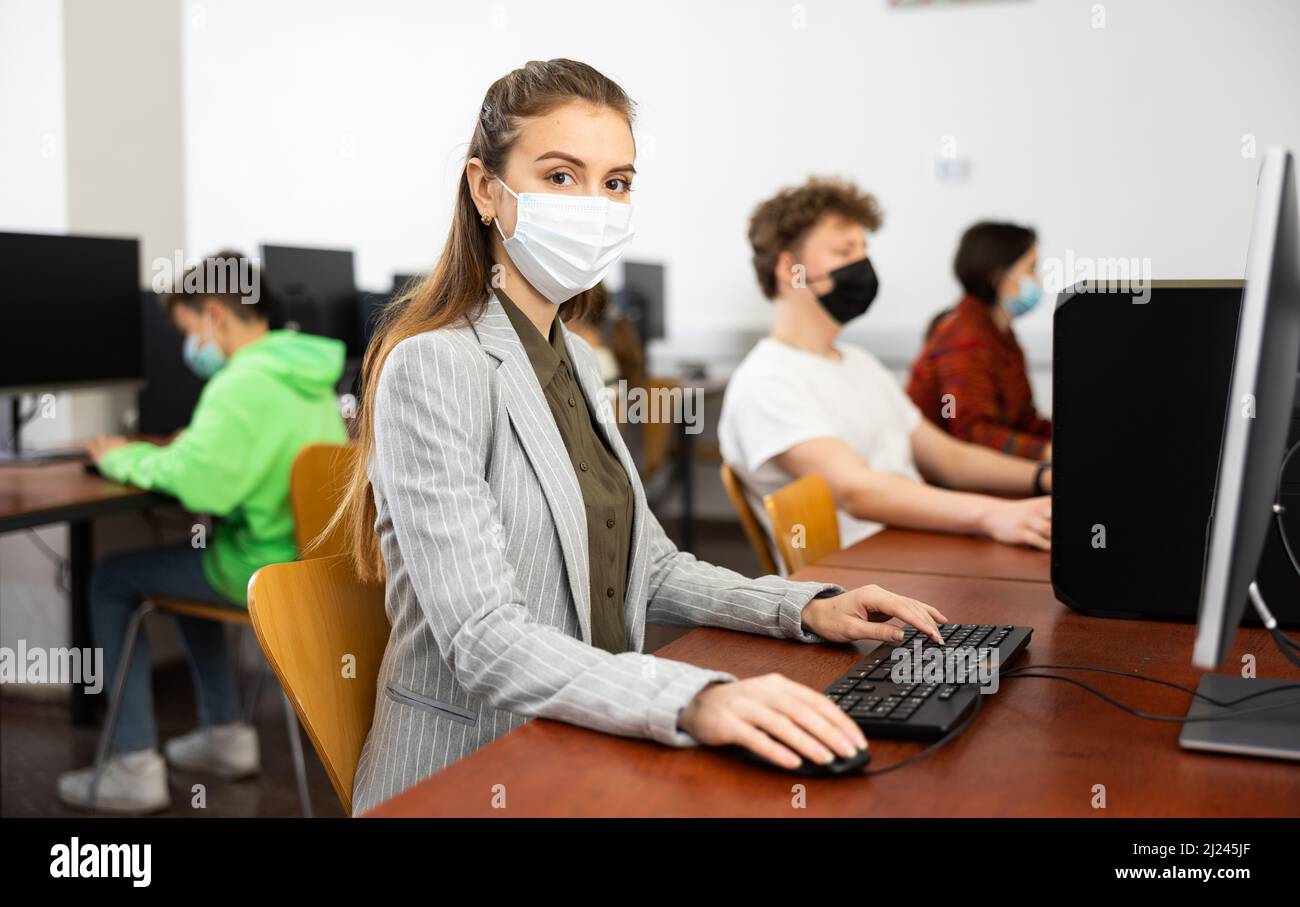 Teacher in mask using computer in classroom Stock Photo - Alamy