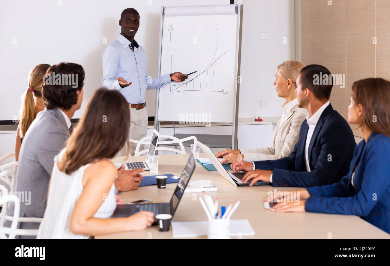African man presenting business project to coworkers Stock Photo - Alamy
