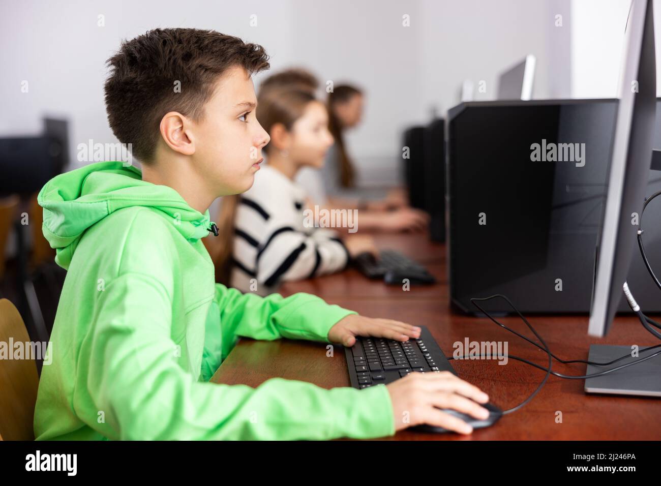Young boy using computer during lesson Stock Photo - Alamy