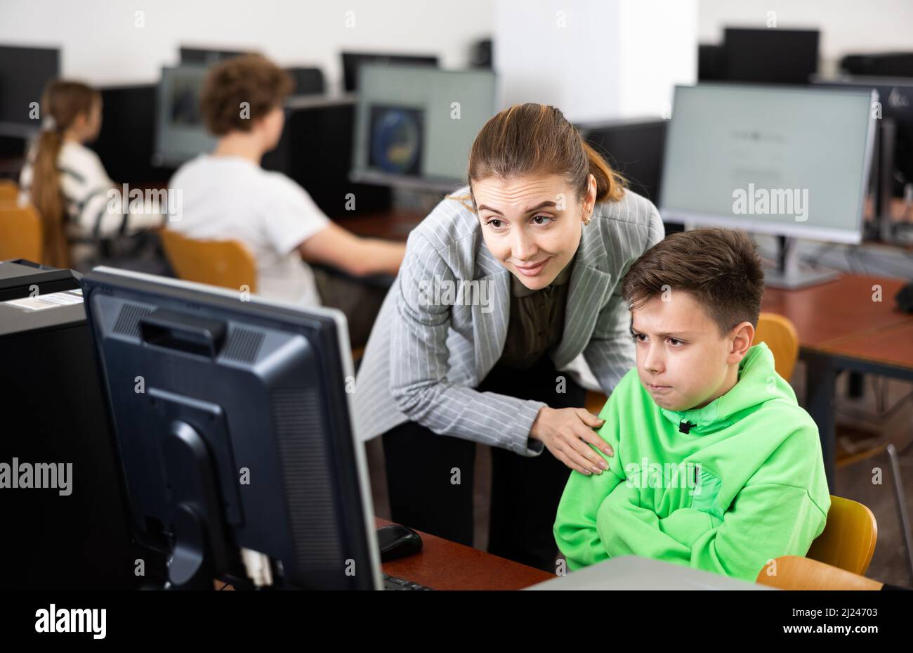 Teacher helping boy to solve computer problem Stock Photo - Alamy