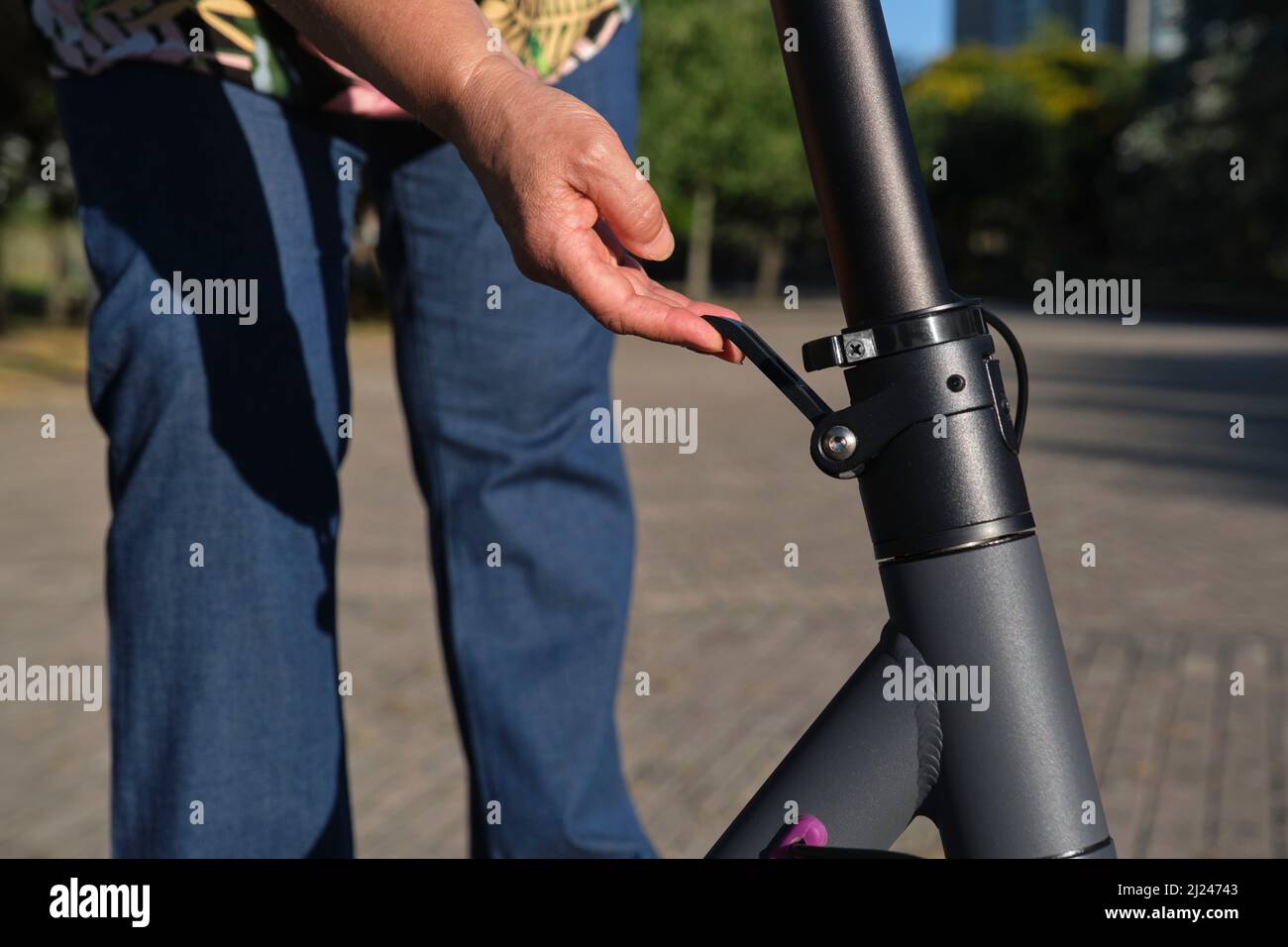 Unrecognizable woman unfolding her electric kick scooter; detail photo ...