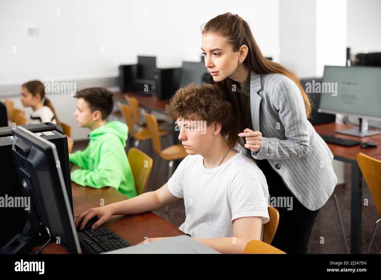 Teacher explaining task solution to pupil during computer science ...