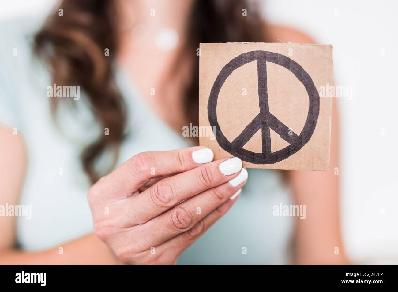 woman holding peace sign on a piece of cardboard pointing it towards ...
