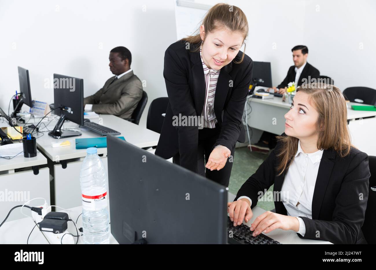 Positive girl helping female colleague in work Stock Photo - Alamy