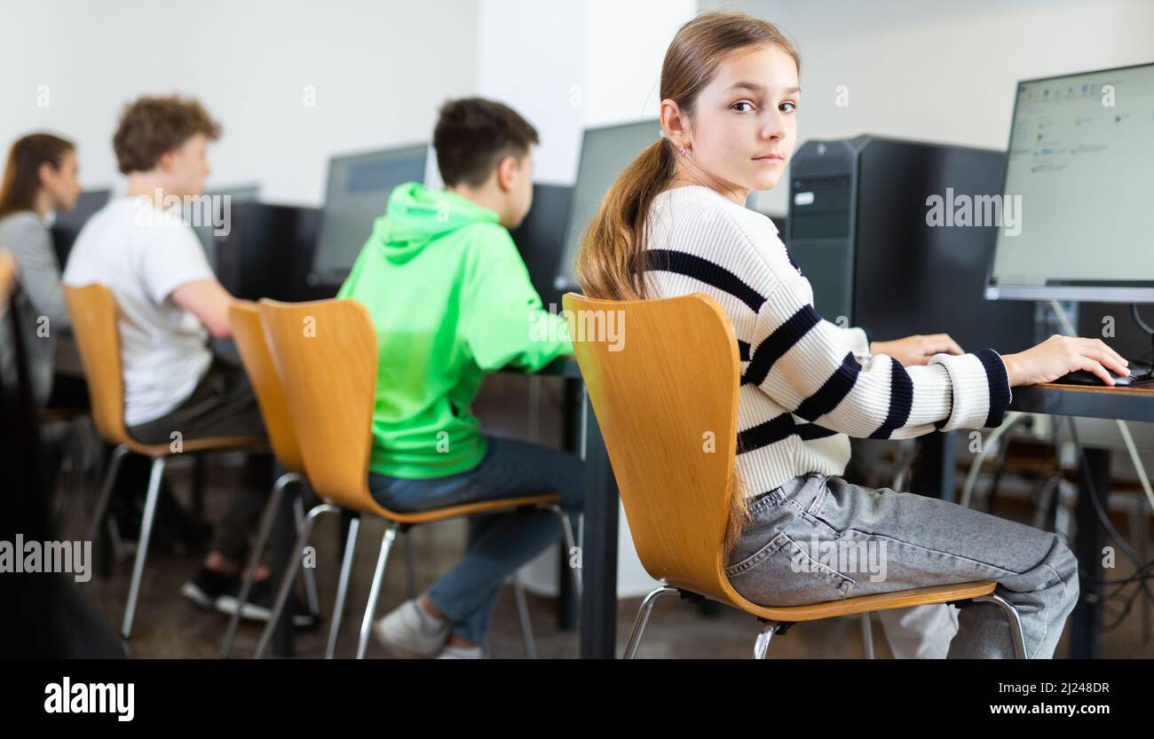 Pupils using computers at lesson, teacher teaching them in class room ...