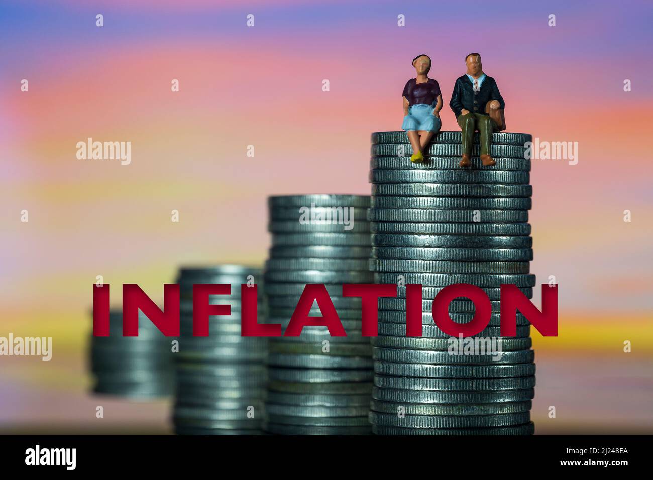 Stack of increasing coins showing the word INFLATION miniature couple ...