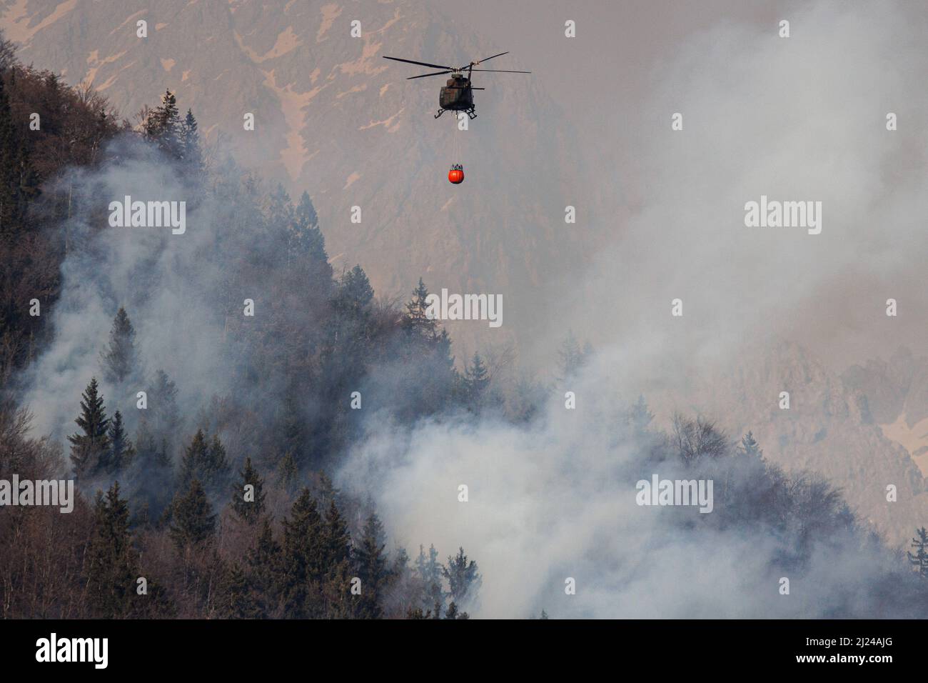 A Slovenian army helicopter carries a Bambi bucket full of water to ...