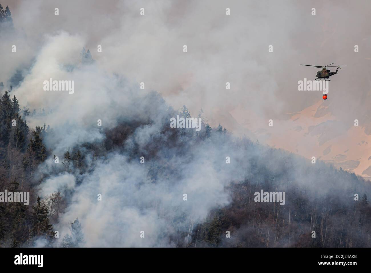 A Slovenian army helicopter carries a Bambi bucket full of water to ...