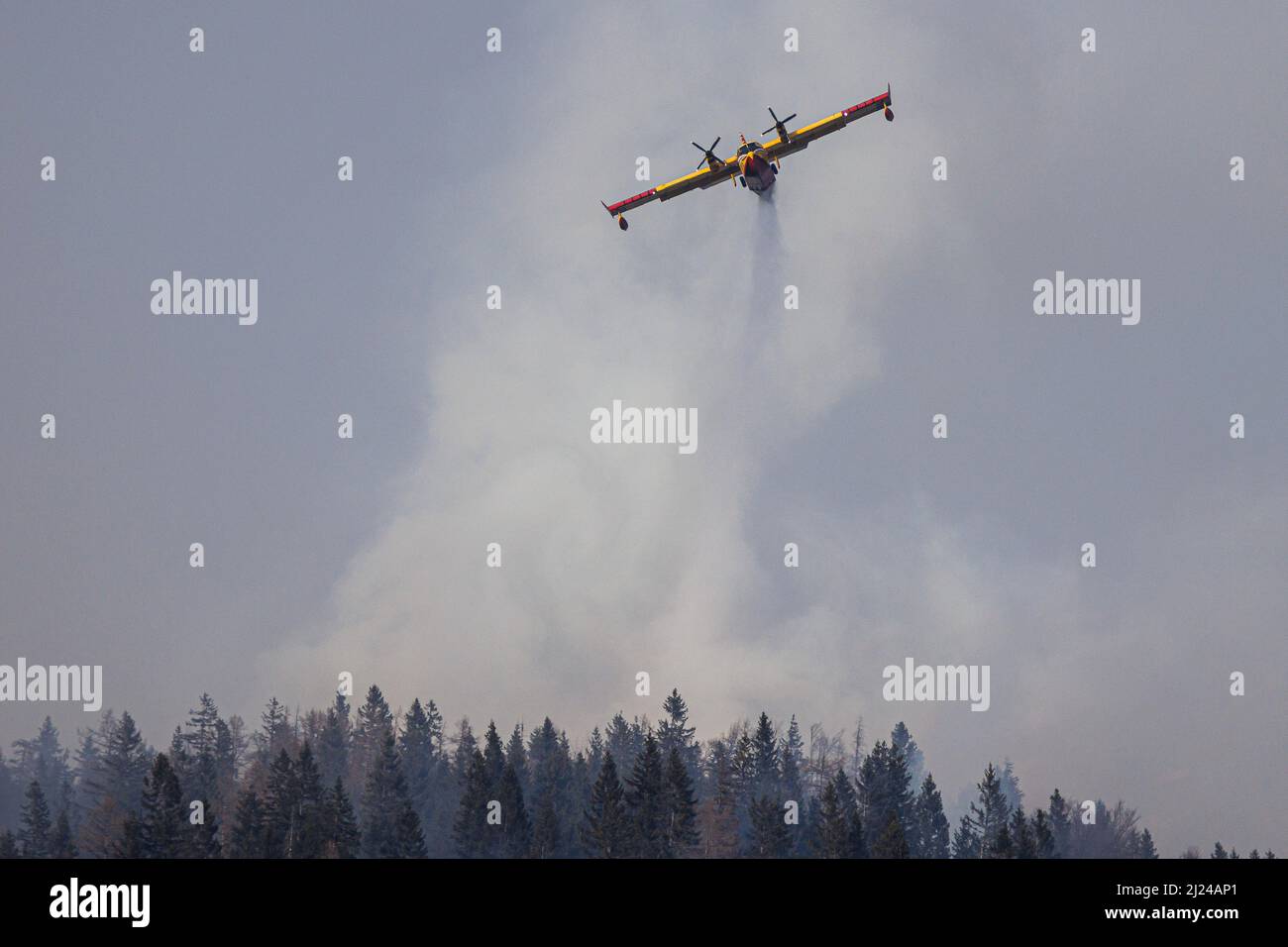 A Croatian Canadair CL-415 firefighting plane drops water on a wildfire ...