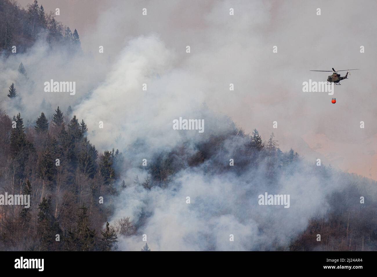 A Slovenian army helicopter carries a Bambi bucket full of water to ...