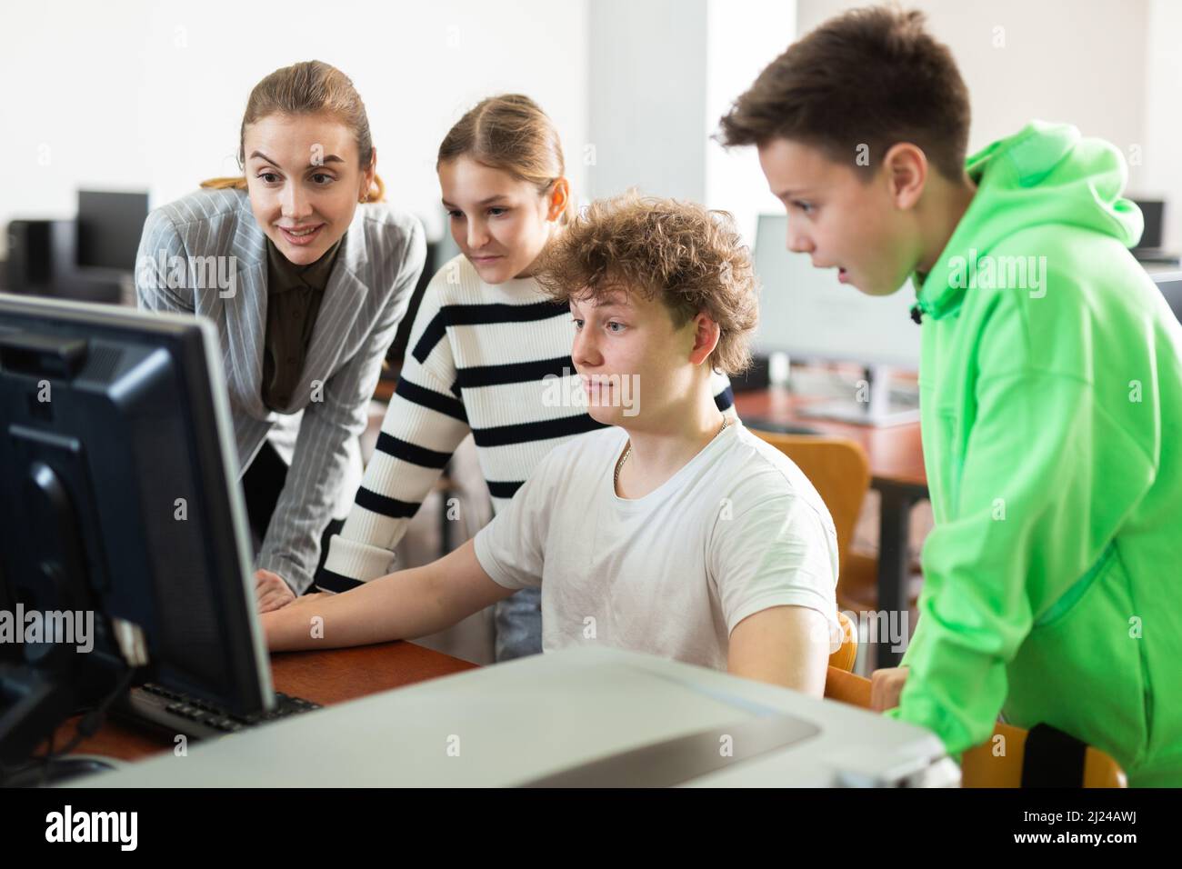 Teacher helping young student in computer class Stock Photo - Alamy