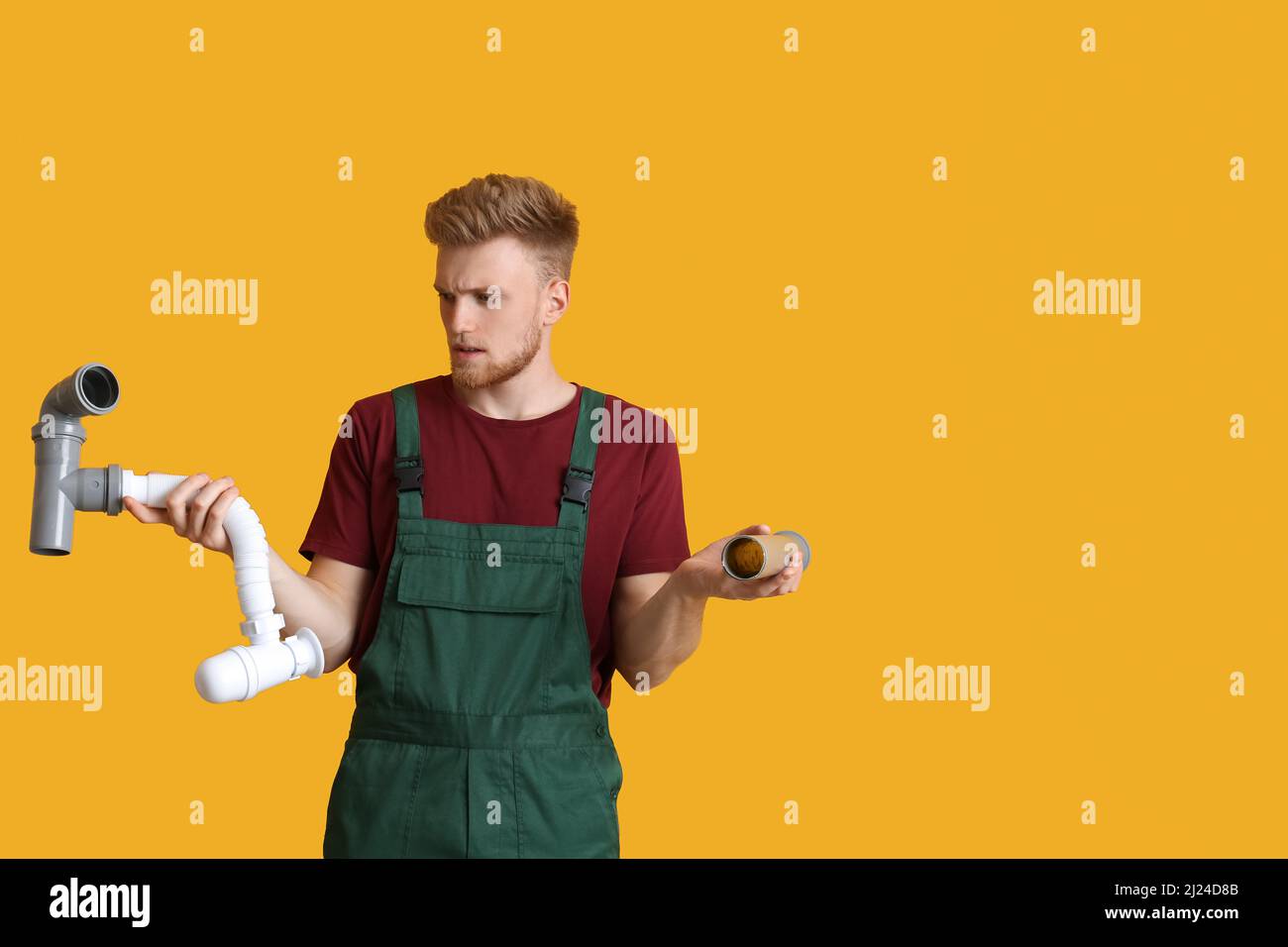 Confused young plumber on color background Stock Photo - Alamy