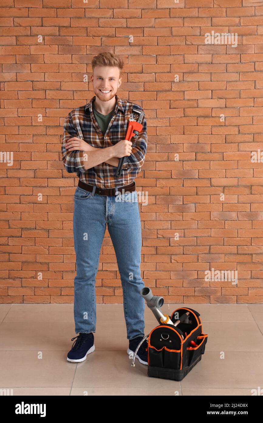 Handsome plumber near brick wall Stock Photo - Alamy