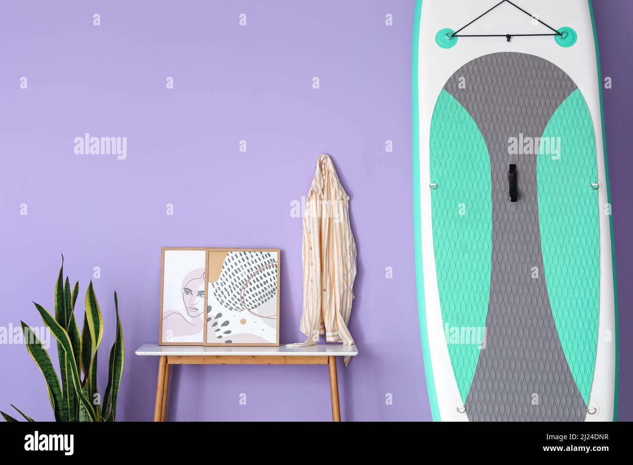 Sup surfing board and table near color wall in room Stock Photo - Alamy