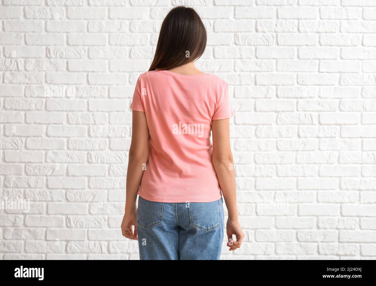 Young woman in blank t-shirt on white brick background, back view Stock ...
