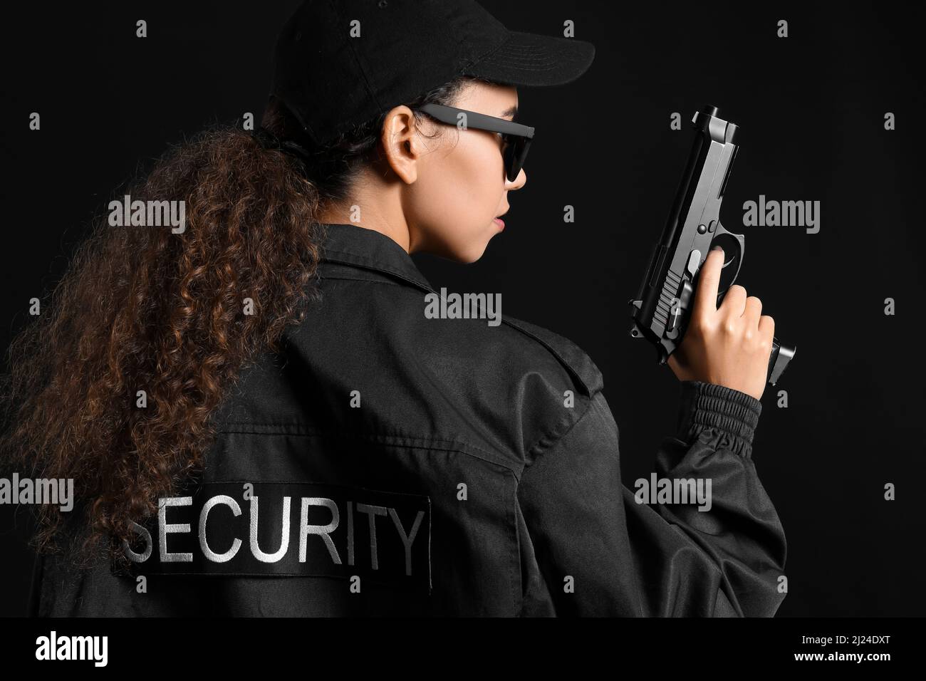African-American female security guard with sunglasses and gun on dark ...