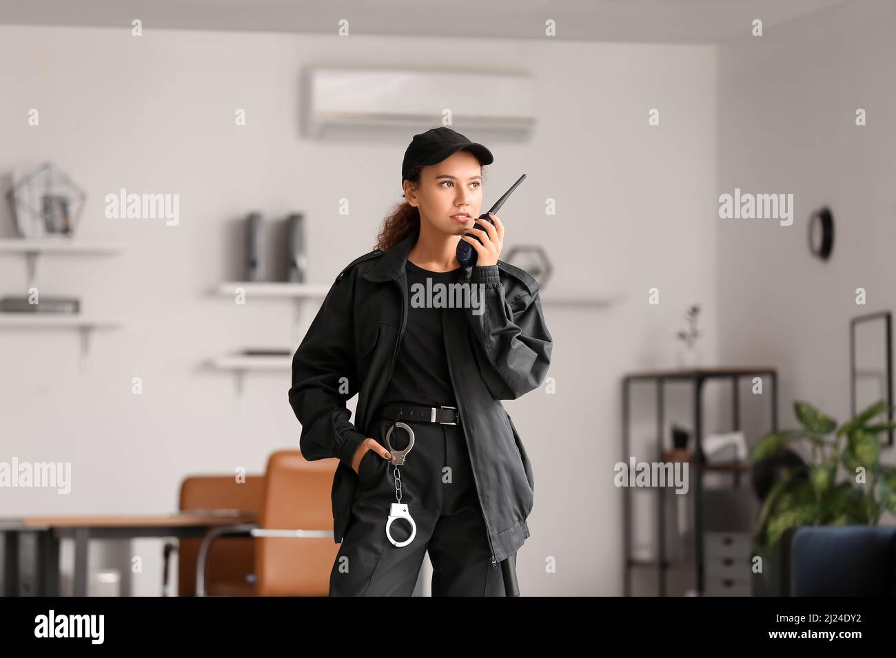 African-American female security guard with radio transmitter in office ...