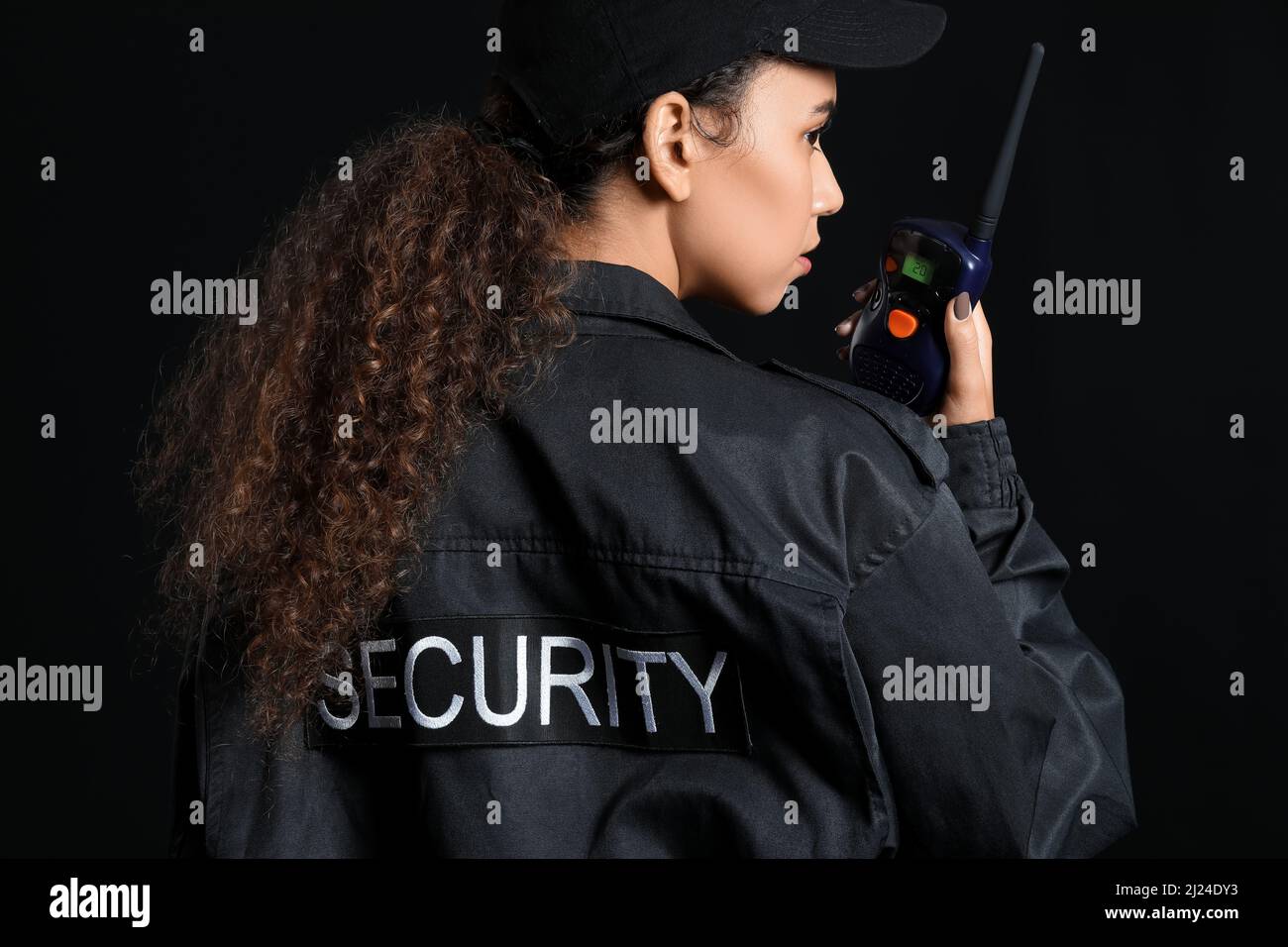 African-American female security guard with radio transmitter on dark ...