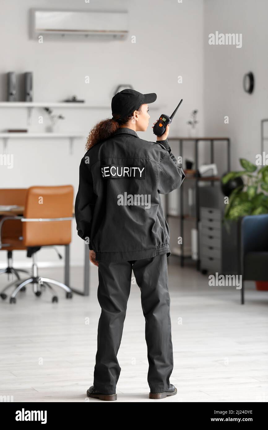 African-American female security guard with radio transmitter in office ...