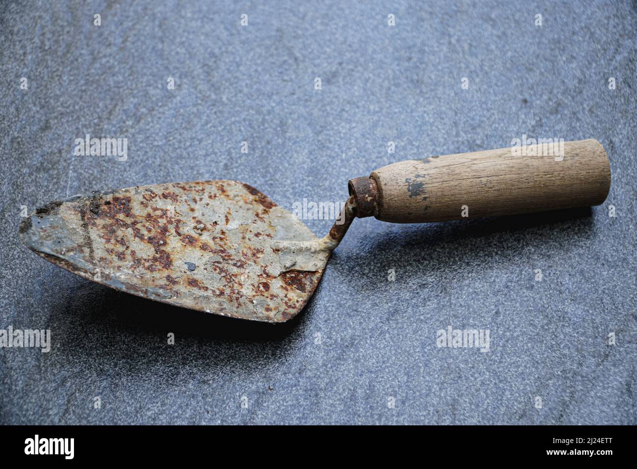 old rusted trowel on grey ceramic background Stock Photo - Alamy