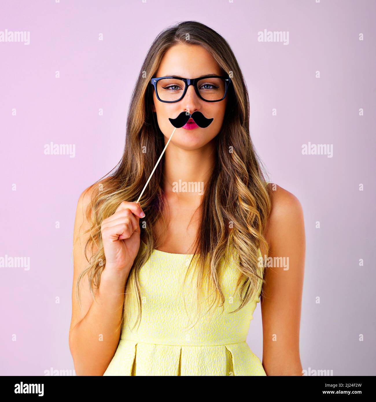 Dont take life too serious. Studio shot of a young woman holding a mustache prop to her face ...