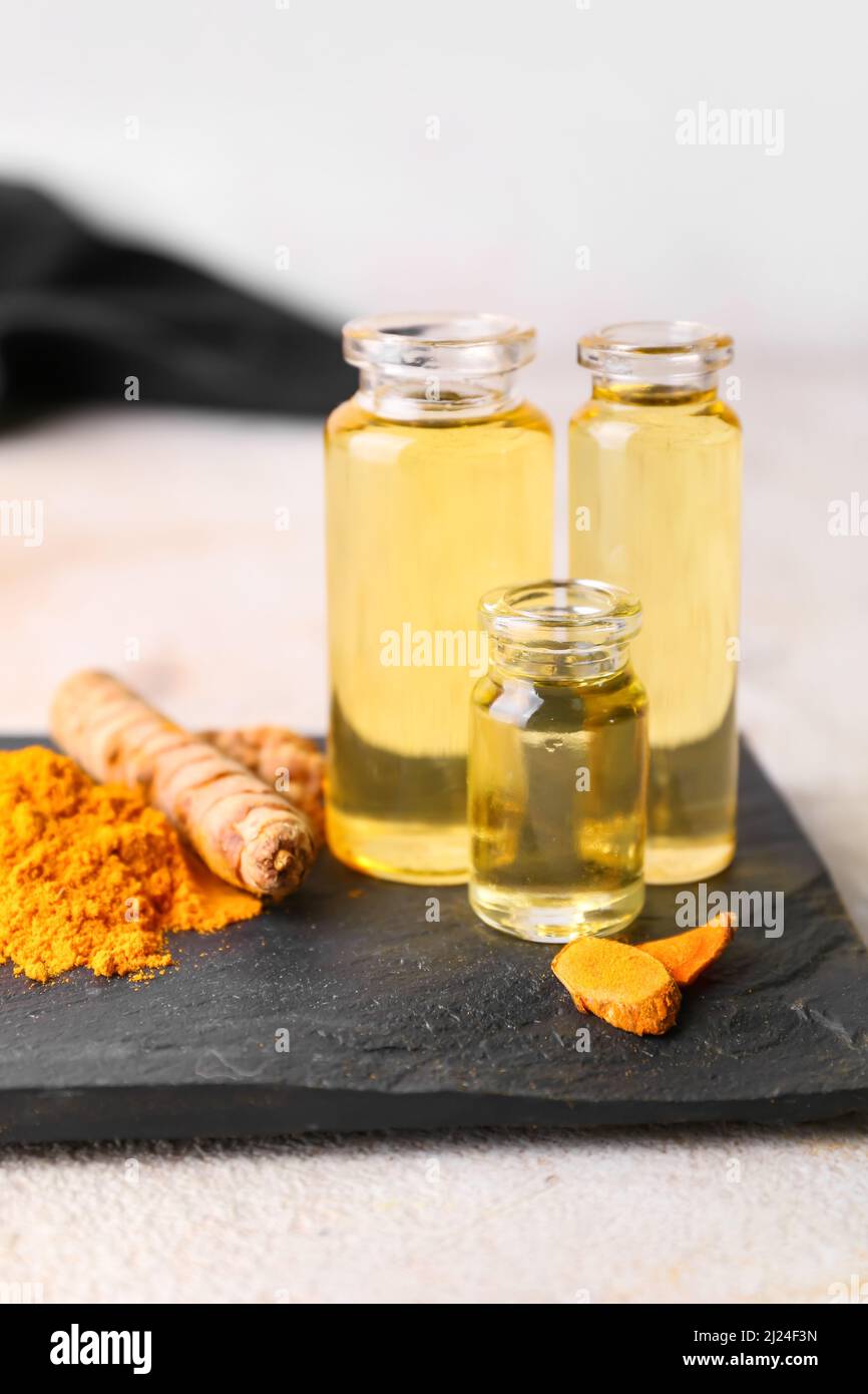 Bottles of oil, turmeric root and powder on light background Stock ...