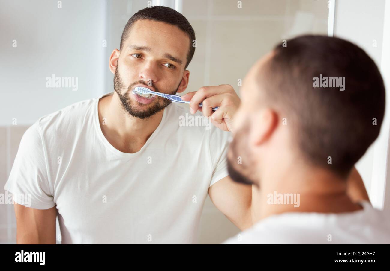 Keeping these choppers pearly white. Shot of a young man brushing his ...
