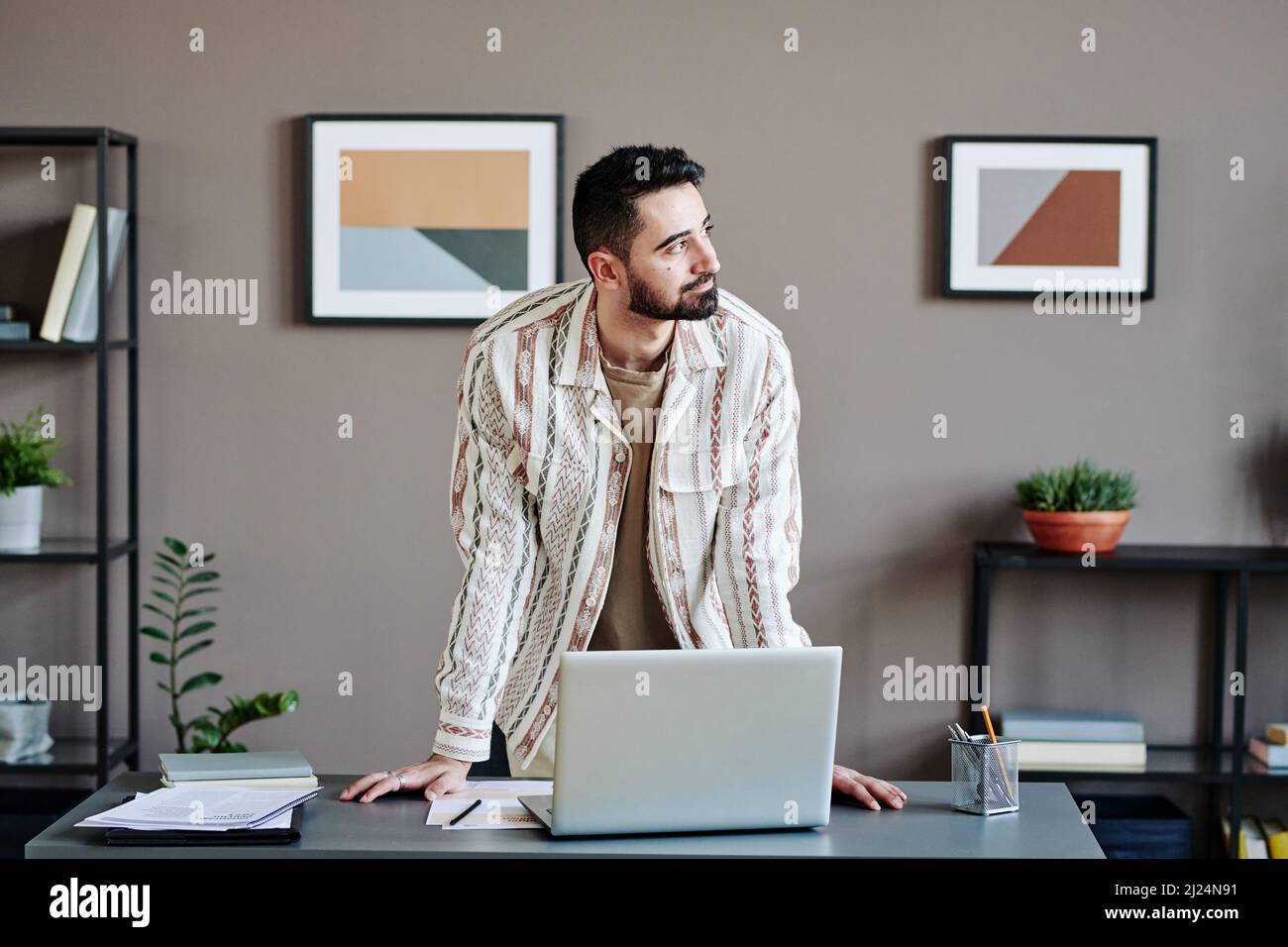 Young contemporary male entrepreneur in casual clothes bending over ...
