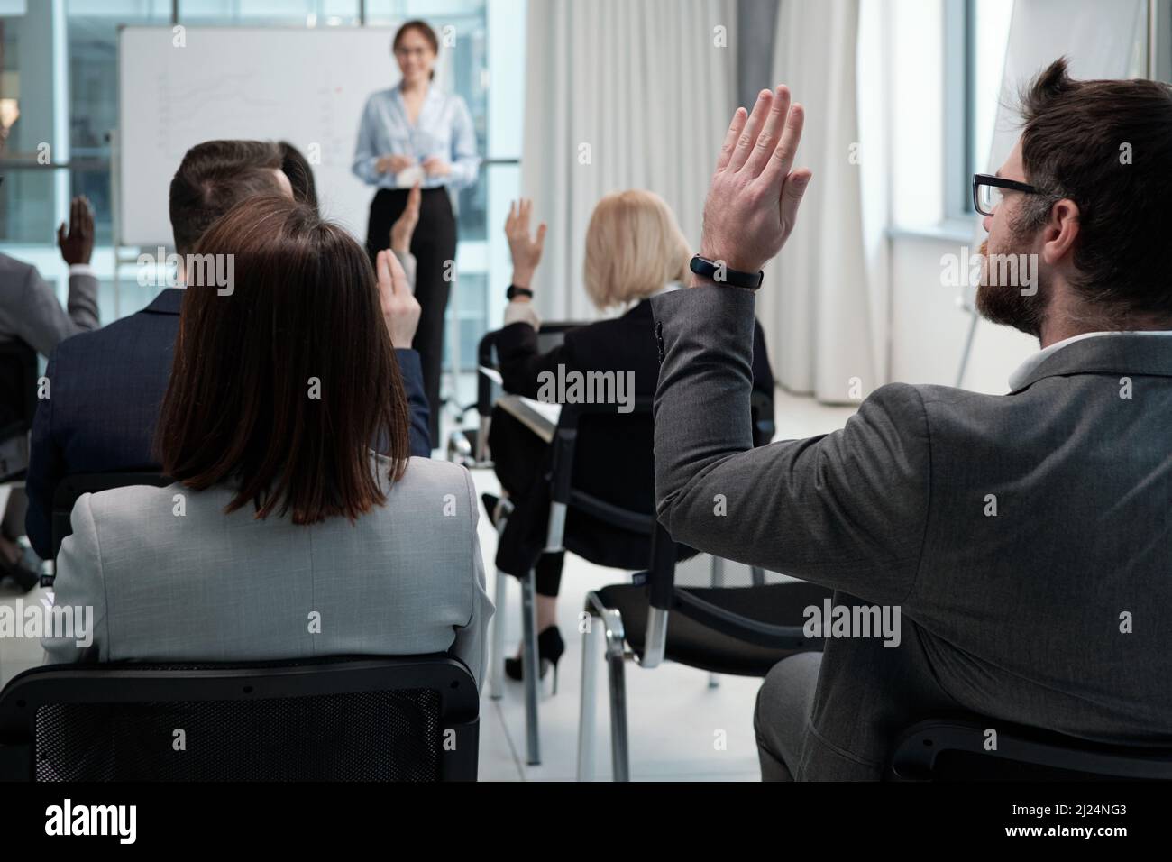 Several contemporary brokers raising hands to ask questions of business ...
