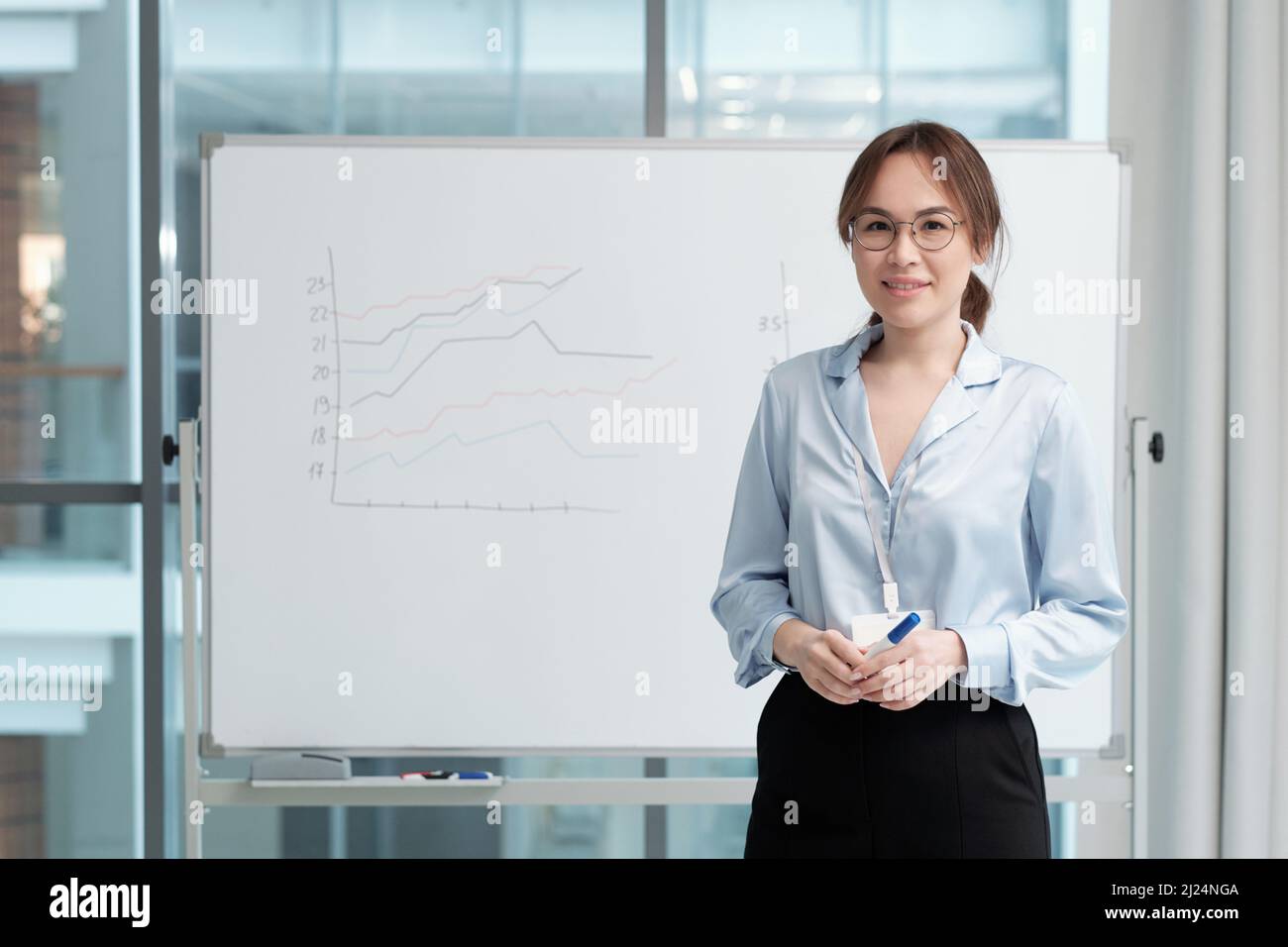 Young successful teacher of economics in formalwear standing by ...