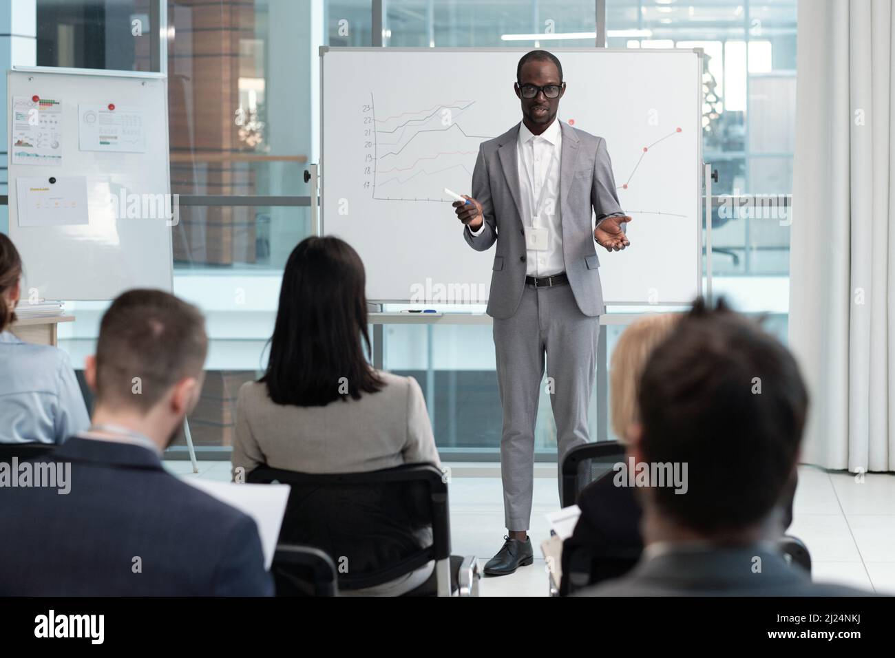 Young African American male coach explaining financial data to audience ...