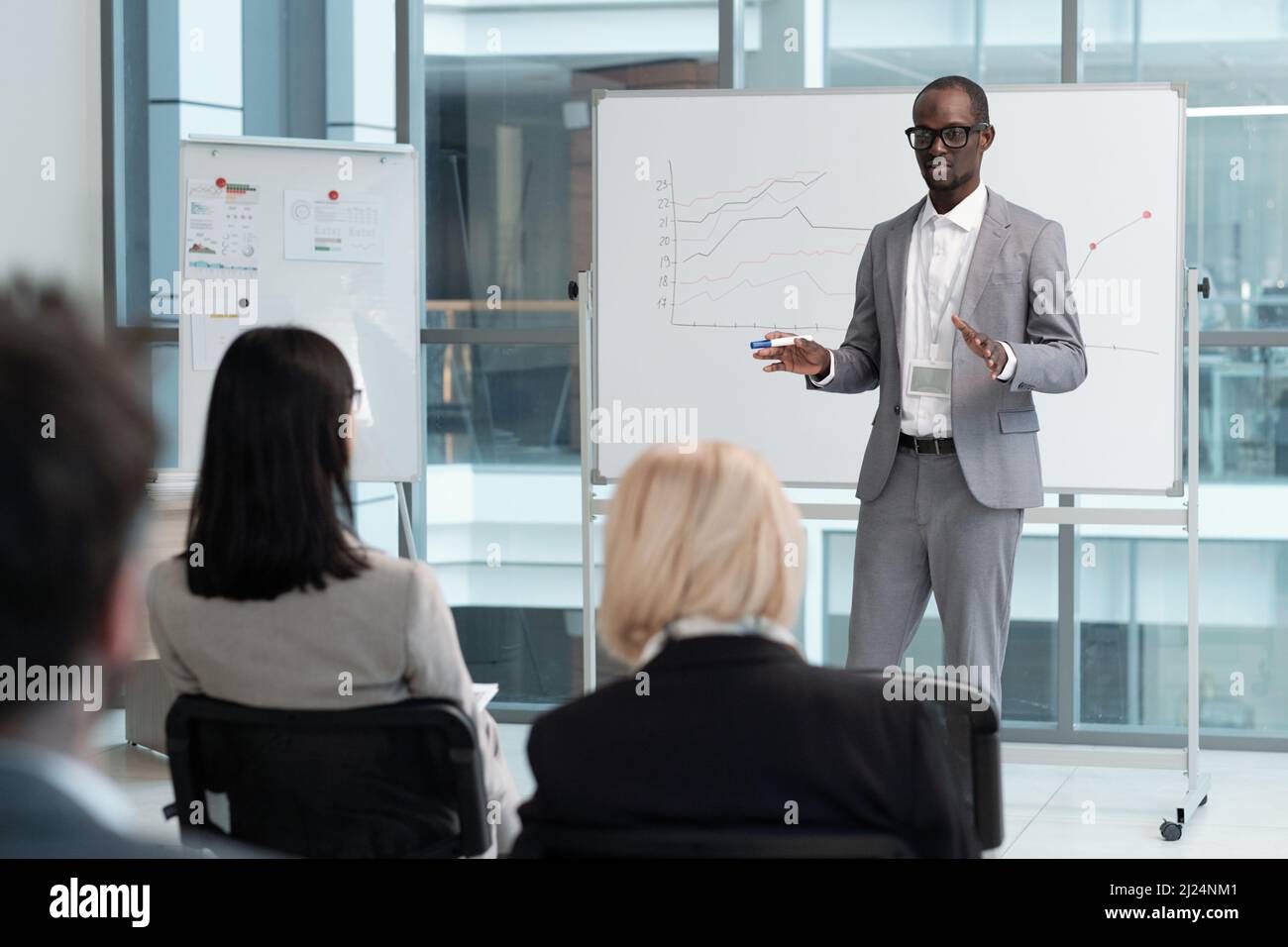 Confident teacher in elegant grey suit explaining audience graphic data ...